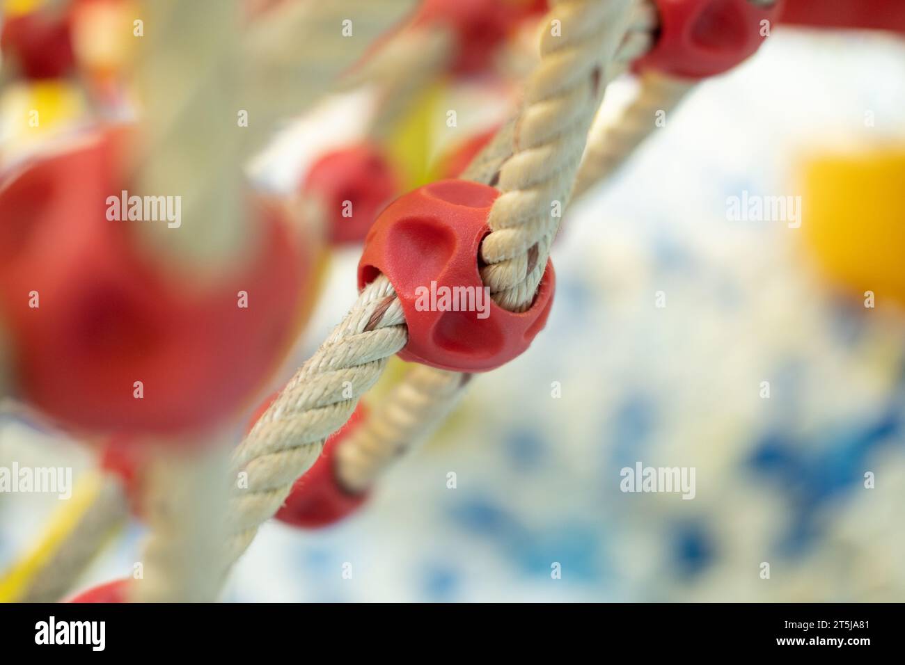 Close-up of a climbing net in a play park with small balls on the floor ...