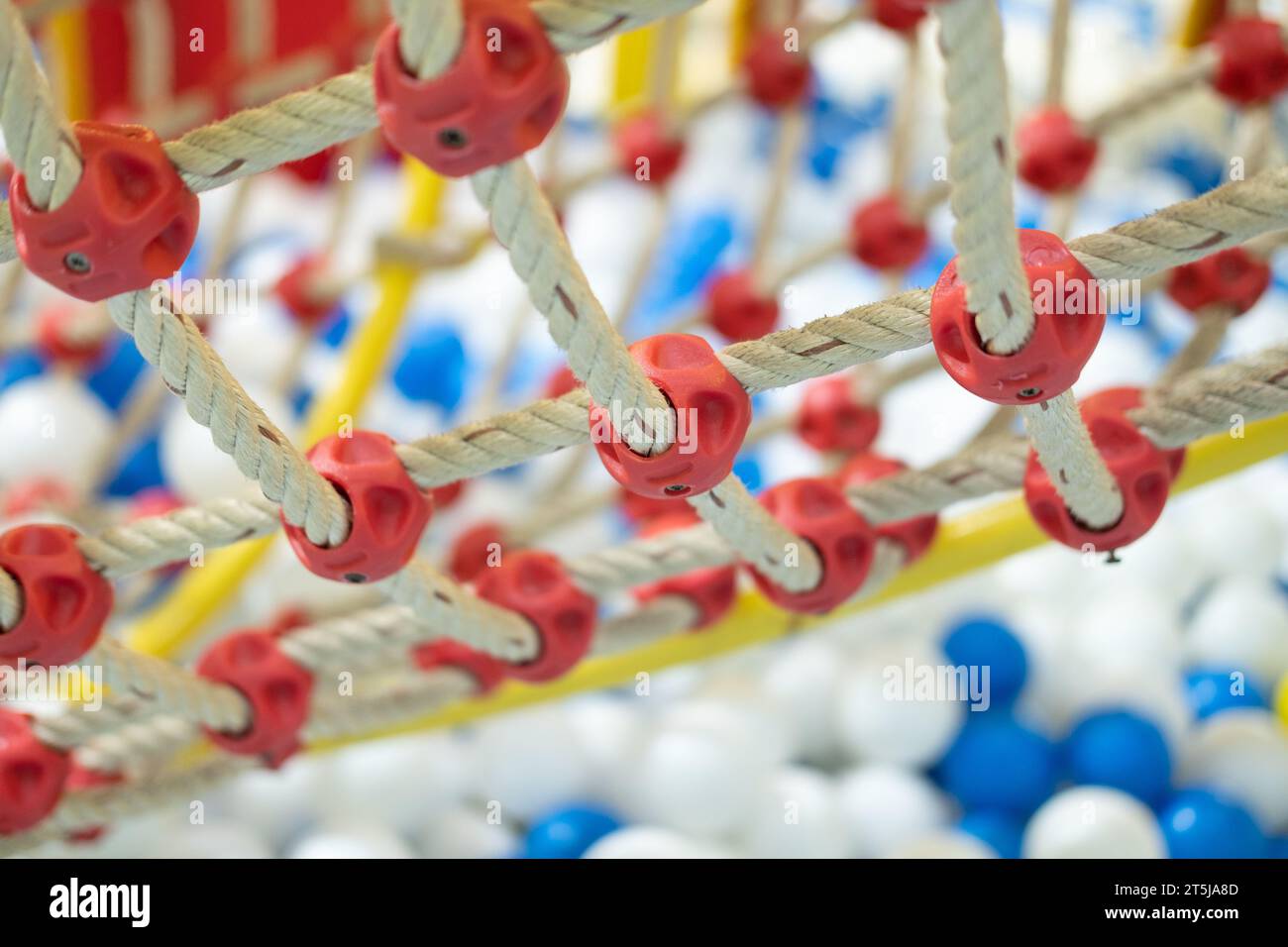 Close-up of a climbing net in a play park with small balls on the floor ...