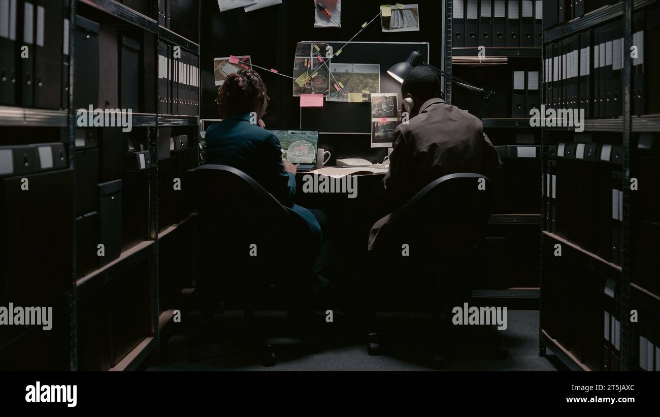 African american agents examining surveillance photos, working on ...