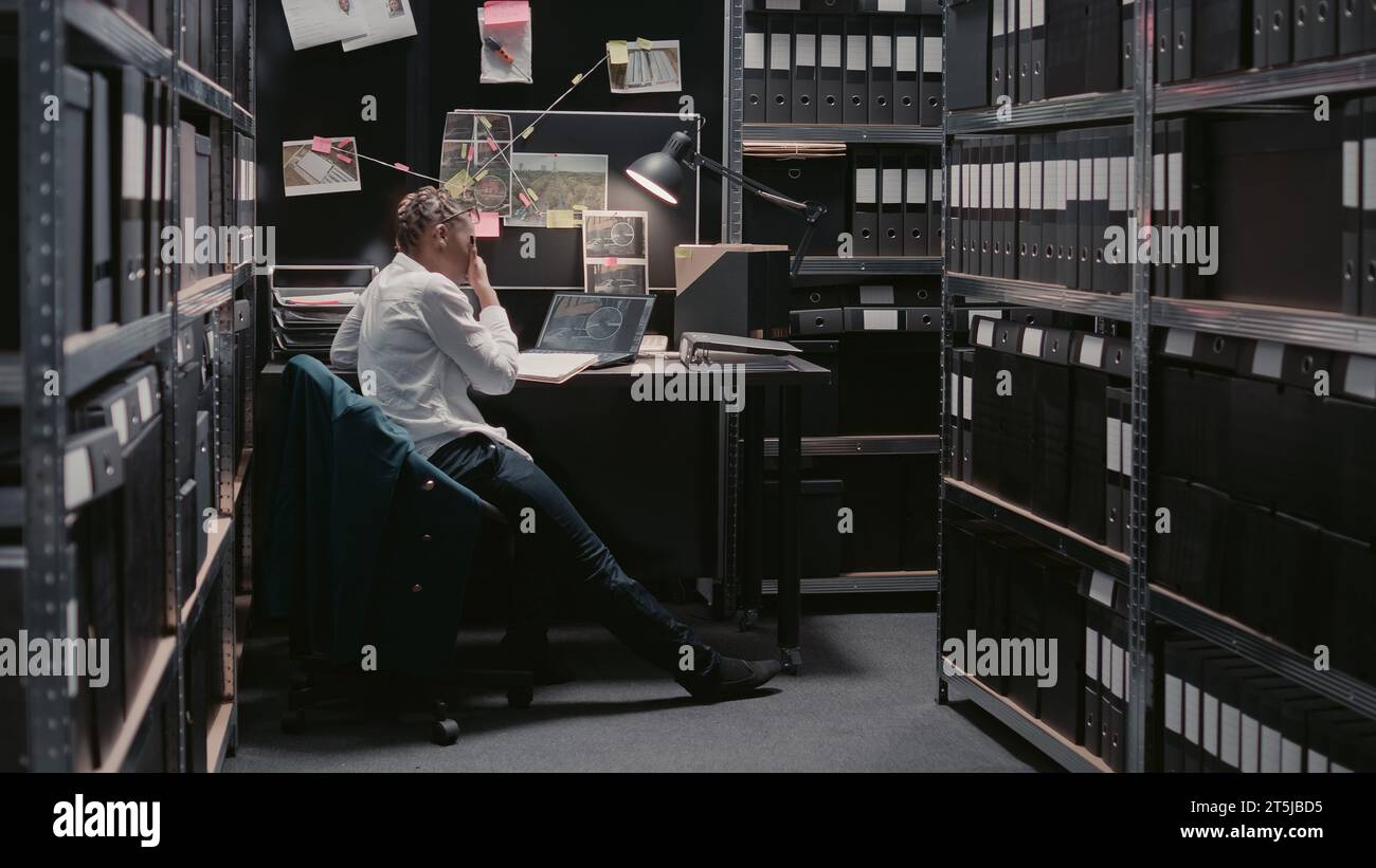 Private officer reading case file information in archive, trying to ...