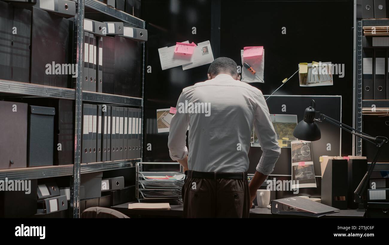 Detective analyzing criminal files and photos on board, searching ...