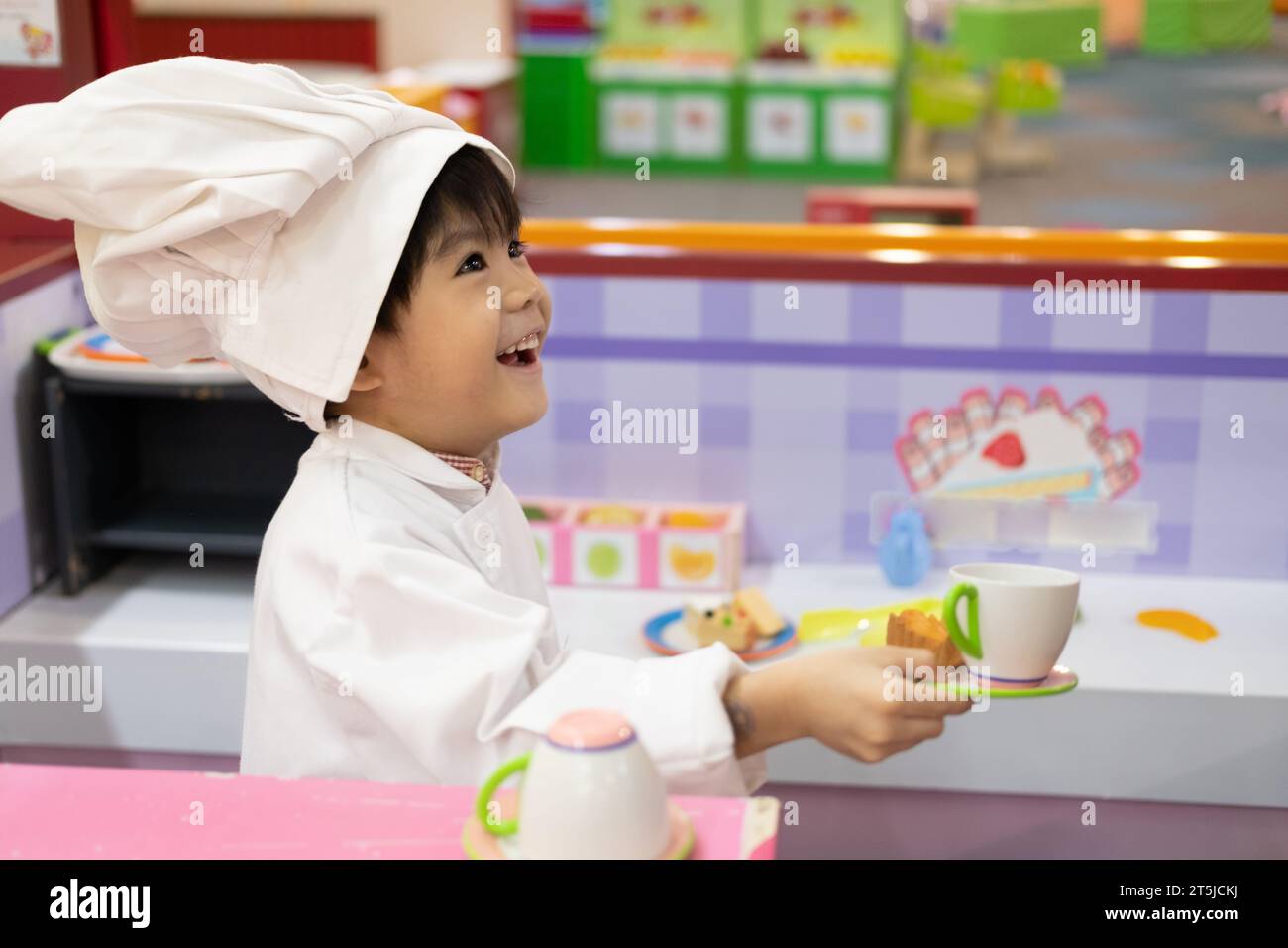Little Asian boy playing chef serving food Stock Photo - Alamy