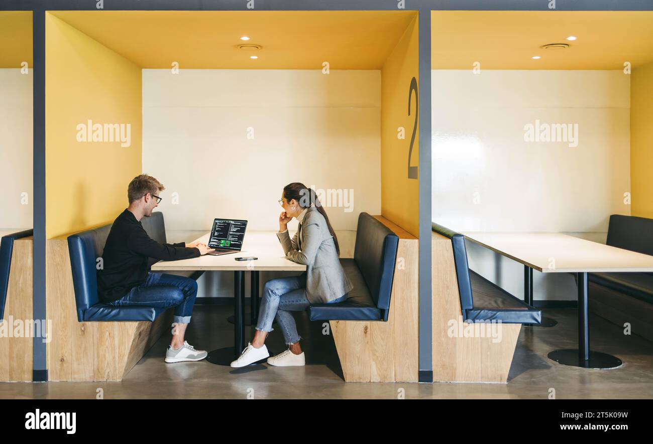 Colleagues in a coworking office discuss a software design and ...