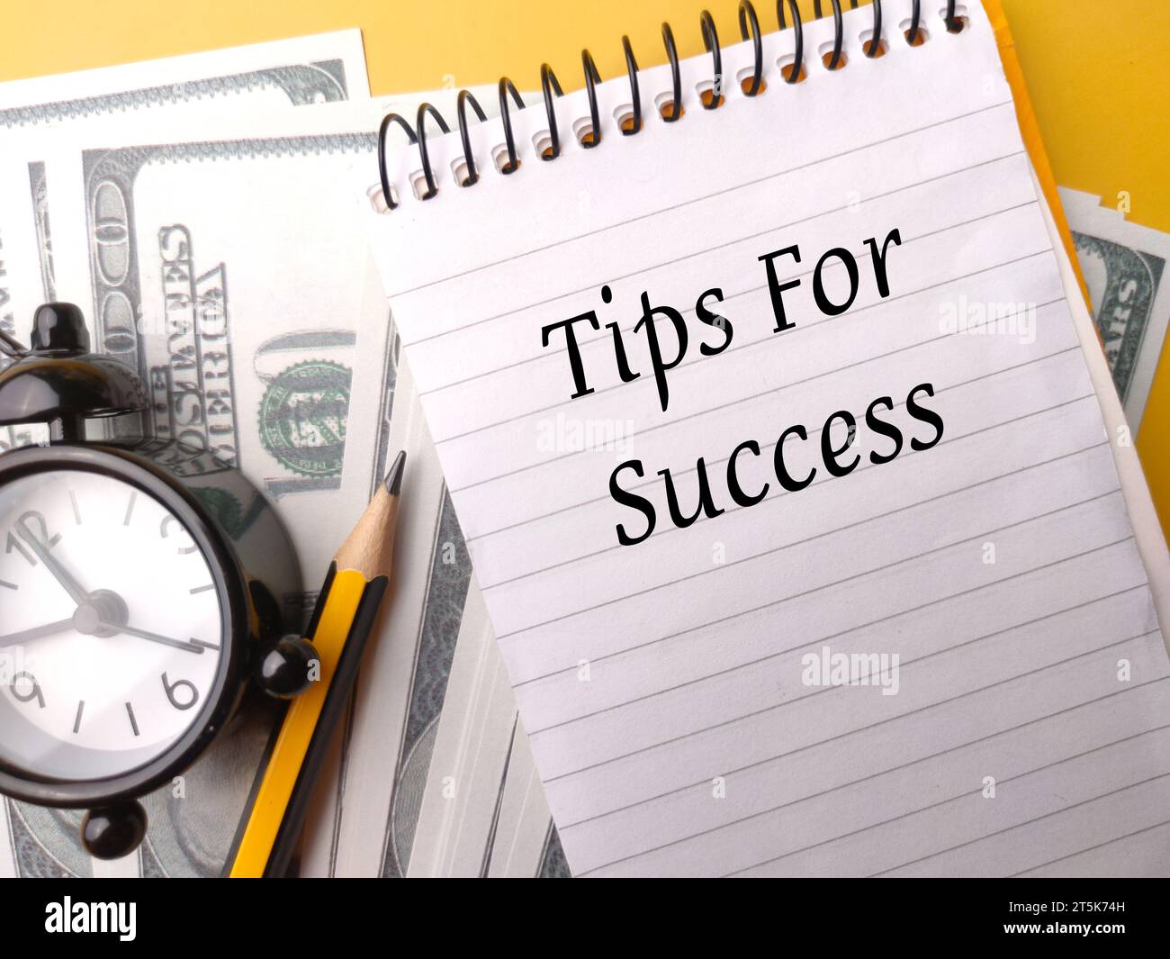 Alarm clock,pencil and banknotes with text Tips For Success on yellow ...