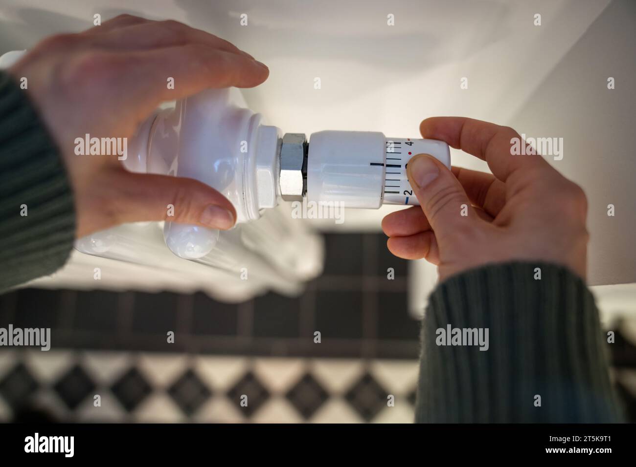 Hands adjusting radiator regulator, increasing temperature in house ...