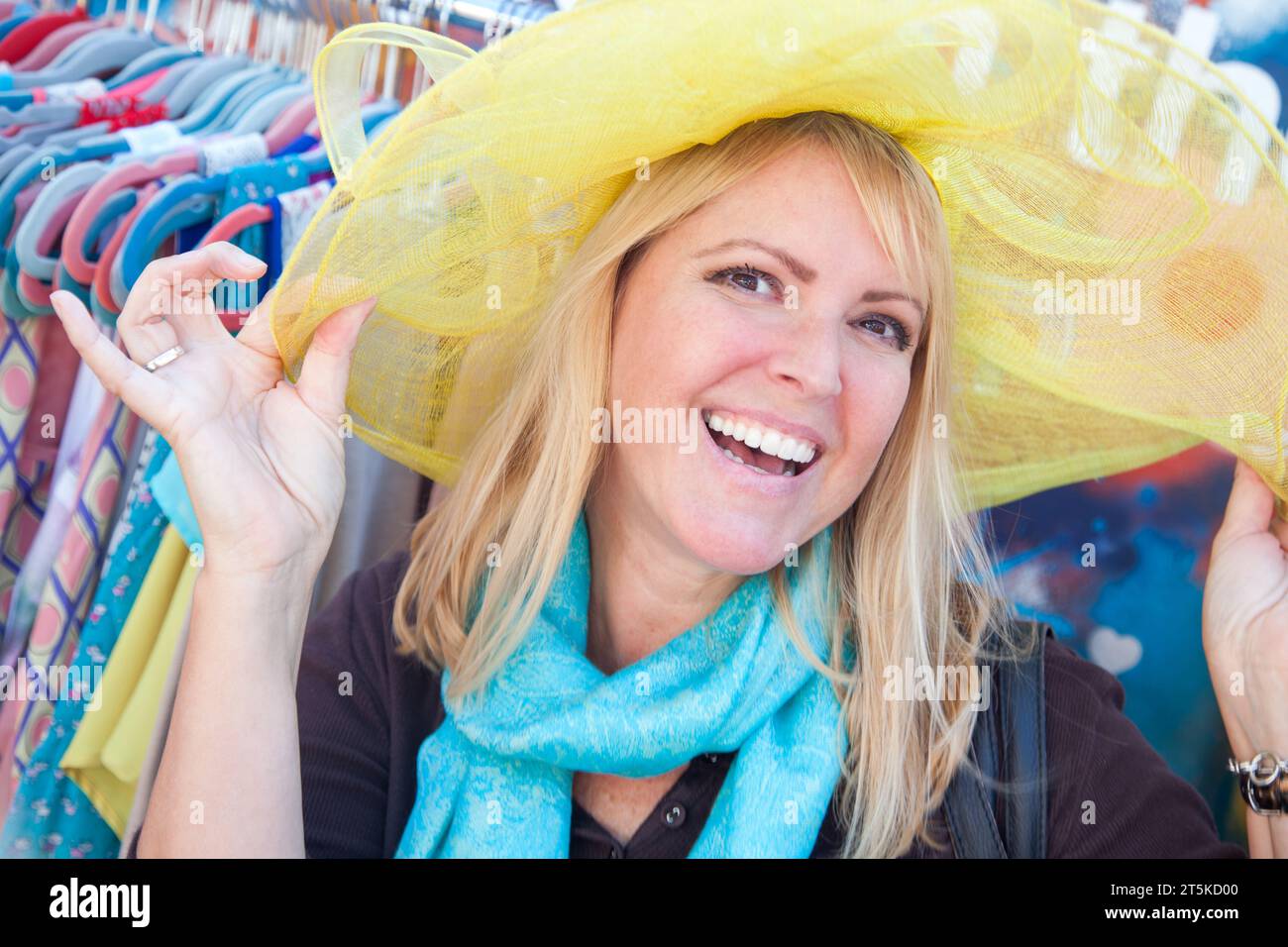 Happy Blonde Woman Playfully Modeling a Big Sun Hat at the Market Stock ...
