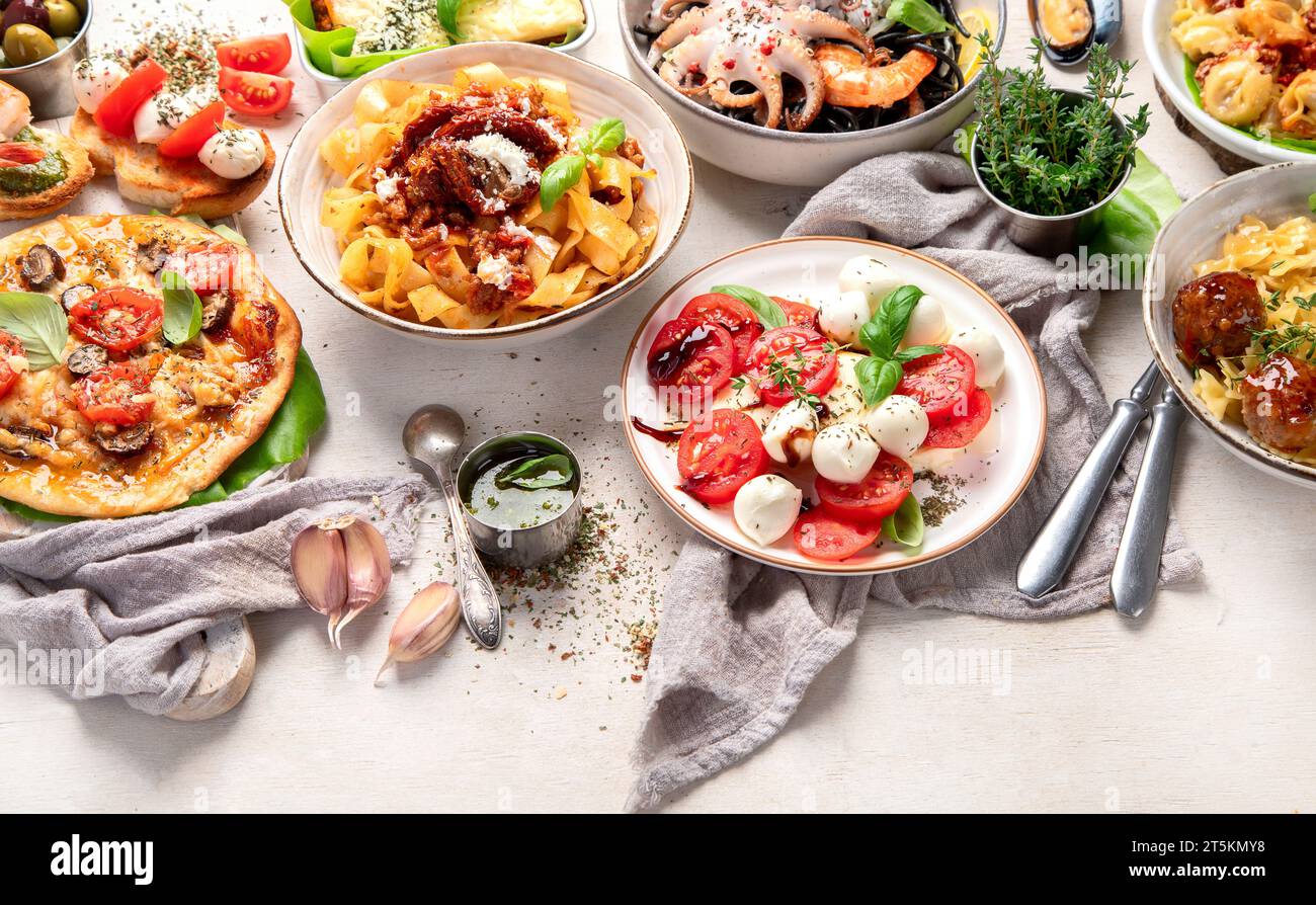 Full table of italian meals on plates Pizza, pasta, ravioli, caprese ...