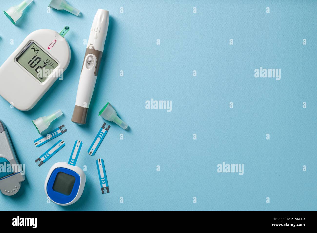 Top view of glucometer, lancet pen and strips on blue background ...