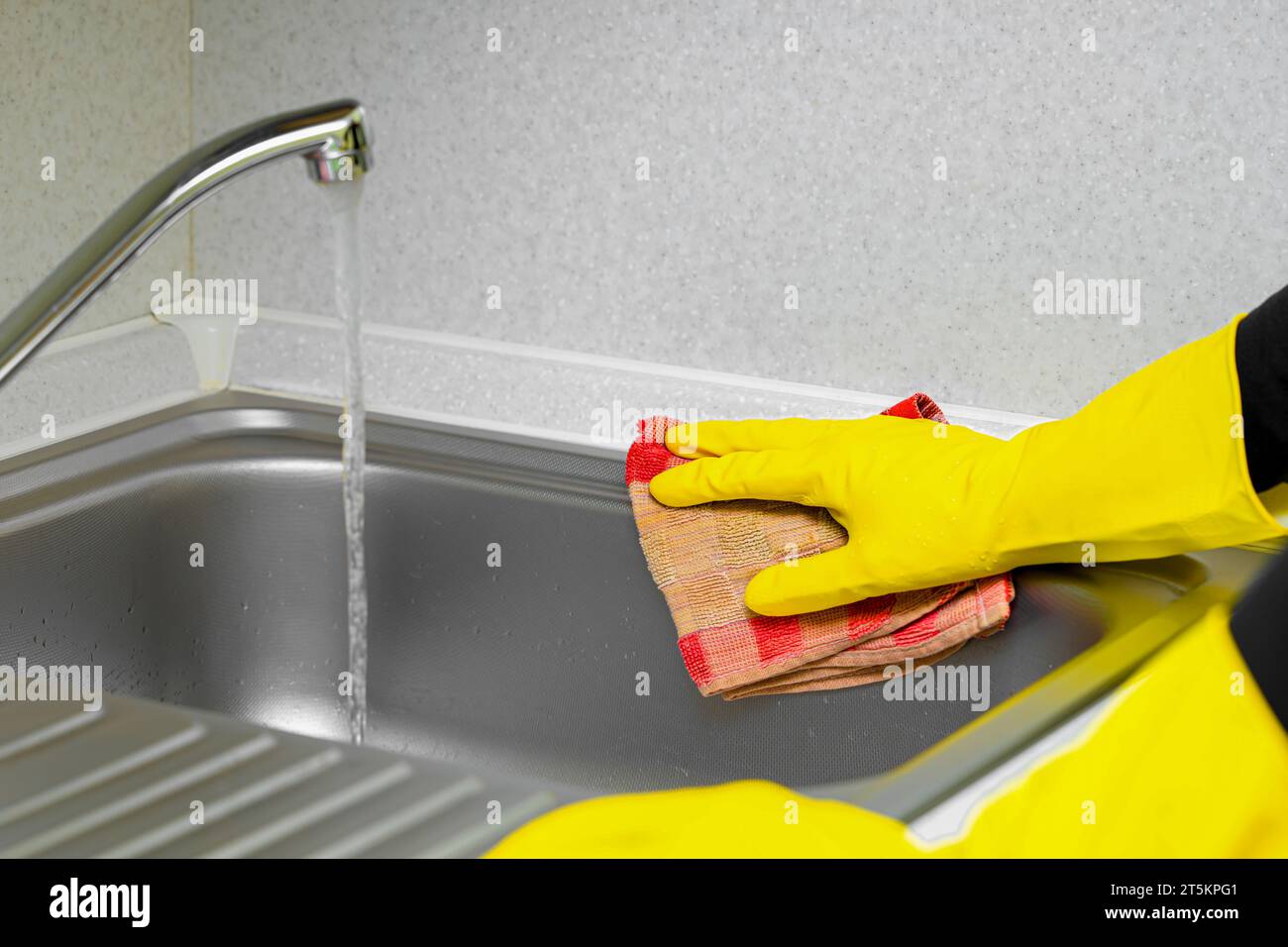 Hand of woman cleaning the kitchen counter and sink at home. woman ...