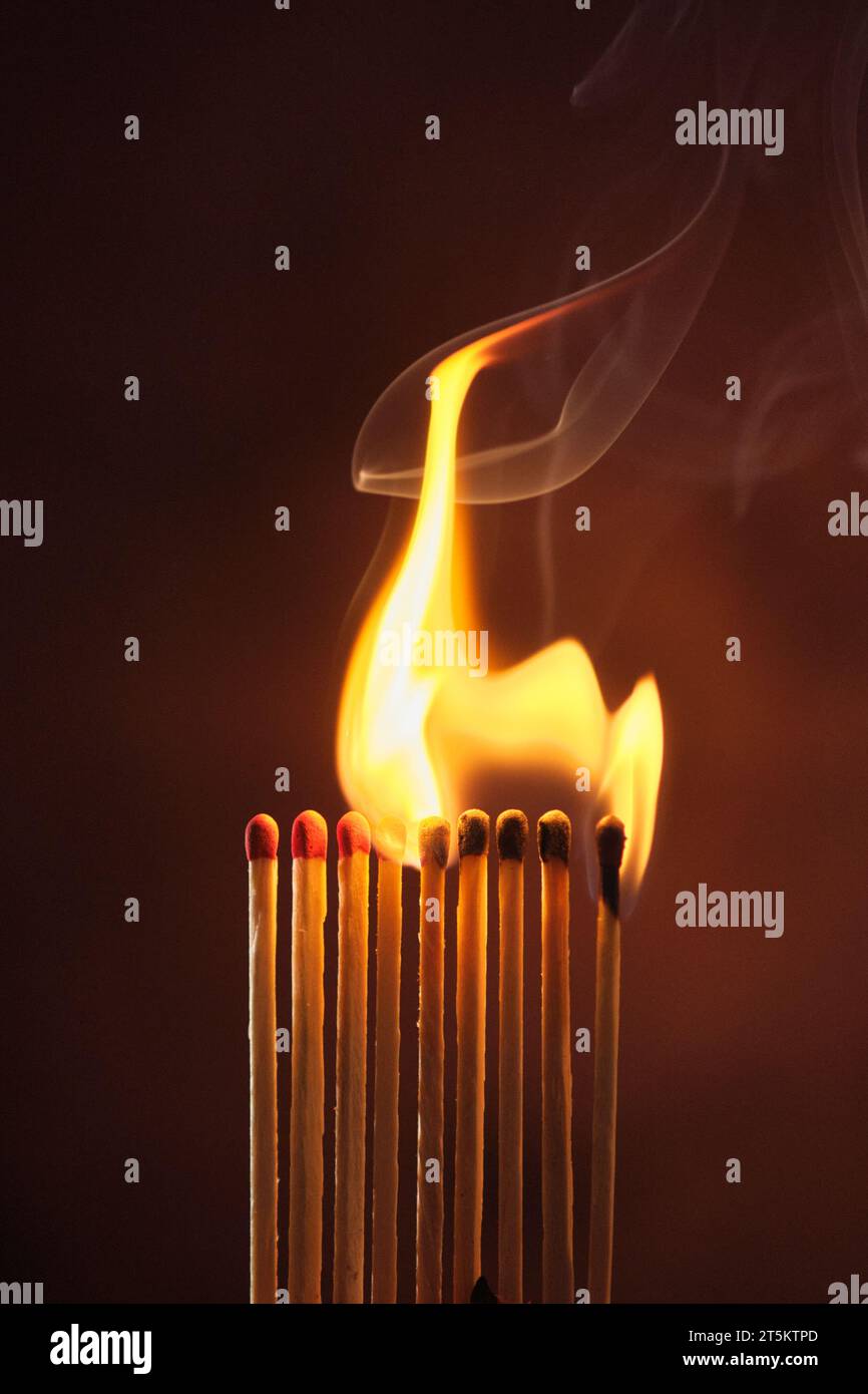 a row of matches are lit on a dark background Stock Photo - Alamy
