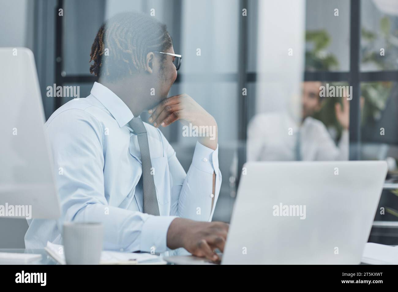 young man working at a computer against the backdrop of a light office ...