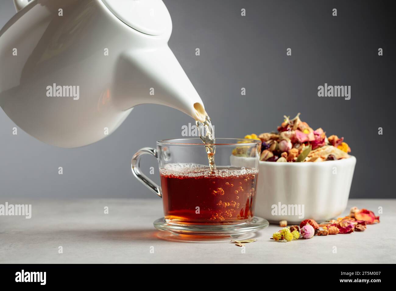 Herbal tea is poured into a mug. Mixtures of dried herbs and flowers ...