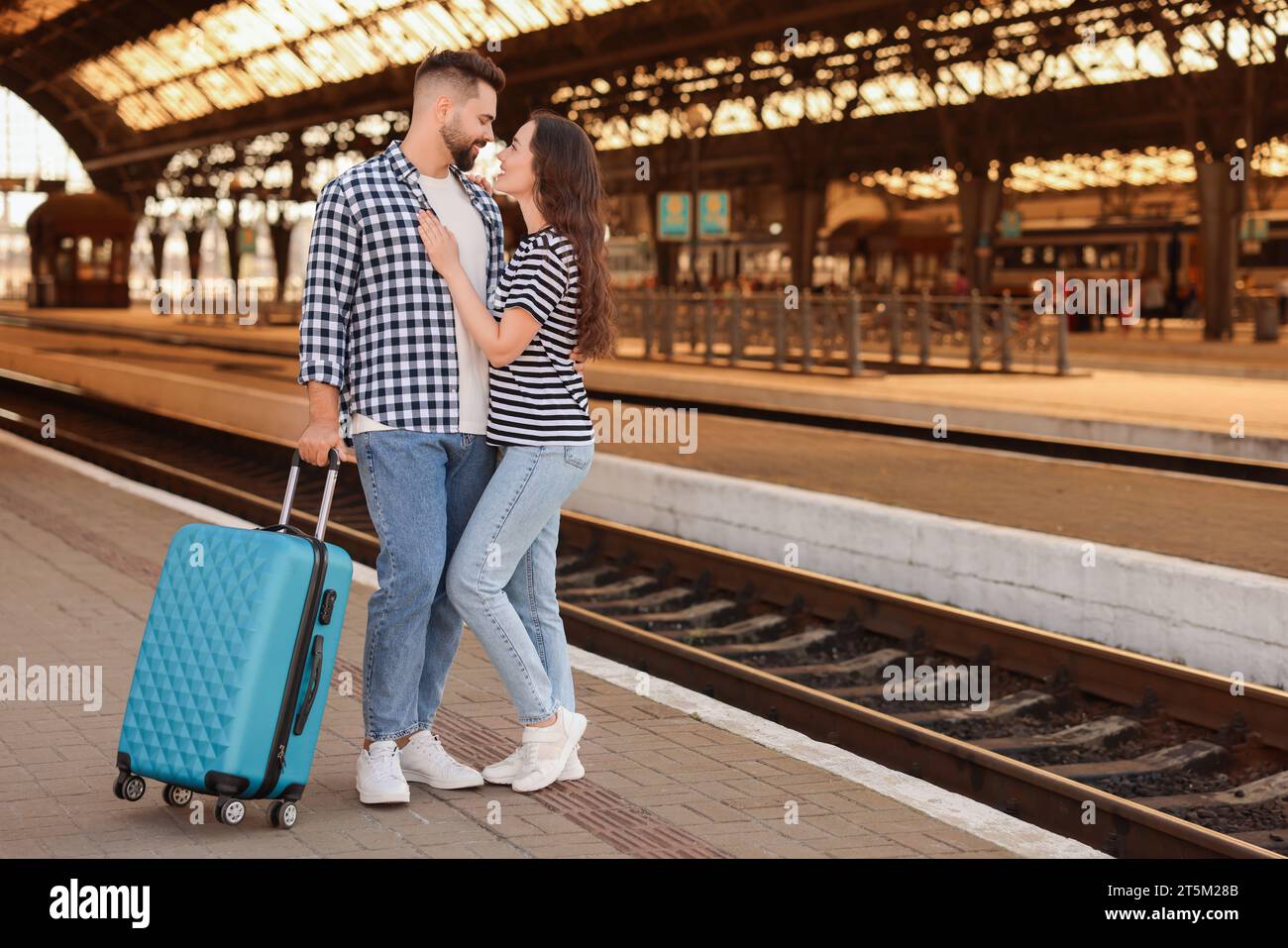 Long-distance relationship. Beautiful couple on platform of railway station, space for text ...
