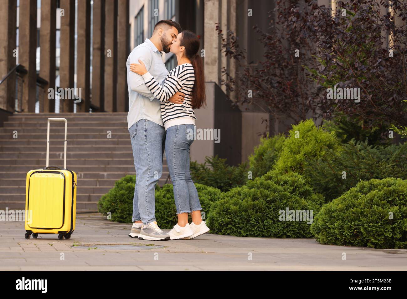 Long-distance relationship. Beautiful young couple kissing and suitcase ...
