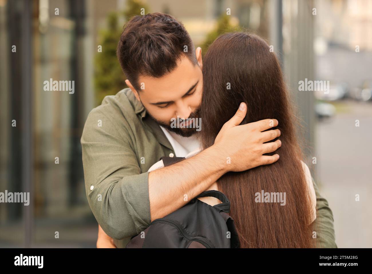 Long-distance relationship. Young couple with backpack hugging outdoors ...
