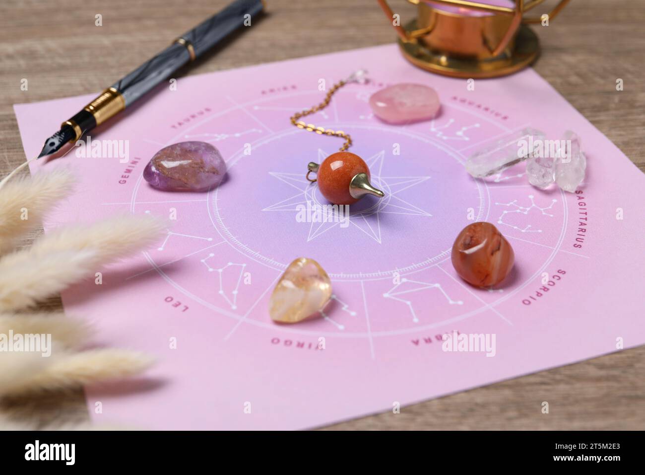 Astrology prediction. Zodiac wheel, gemstones and pendulum on wooden ...
