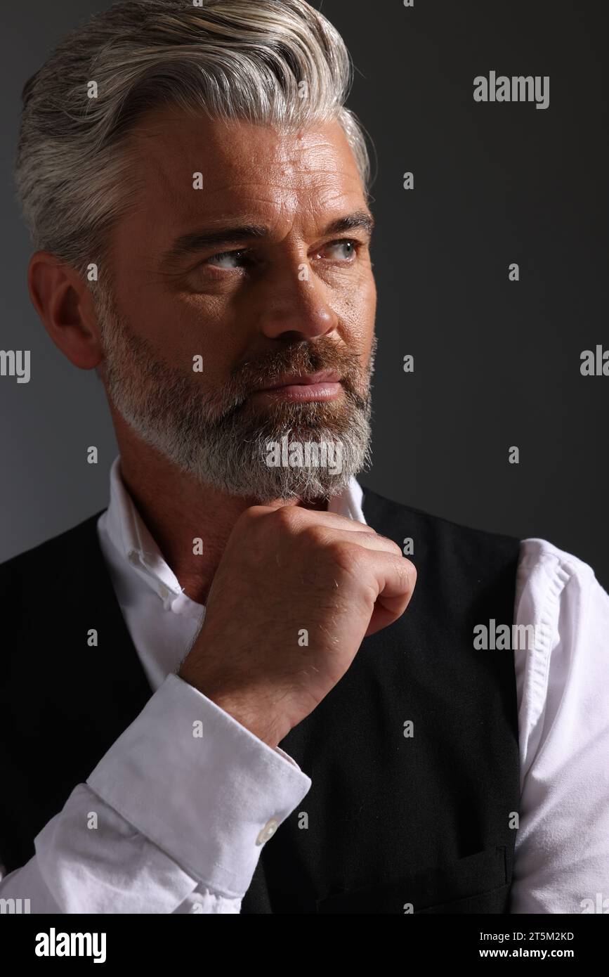 Portrait of confident man with beautiful hairstyle on dark background ...