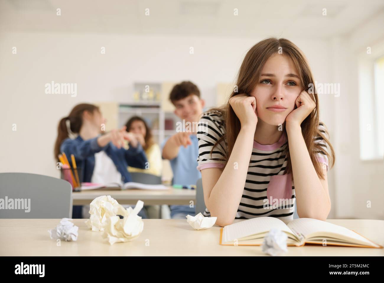 Teen problems. Students pointing at upset girl in classroom, selective ...