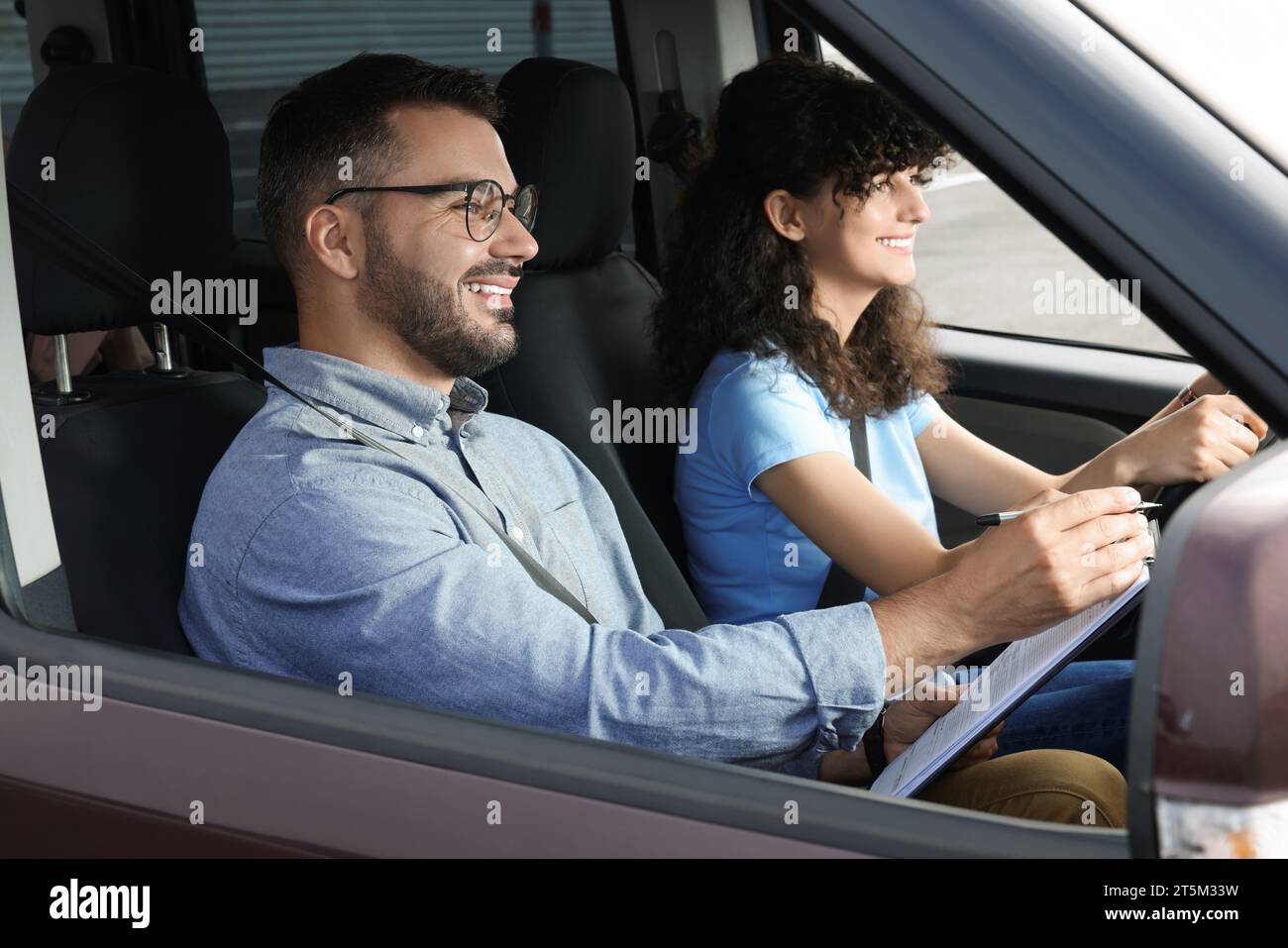 Driving school. Happy student passing driving test with examiner in car ...
