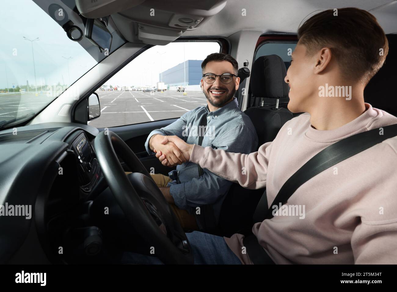 Driving school. Happy student shaking hands with driving instructor ...