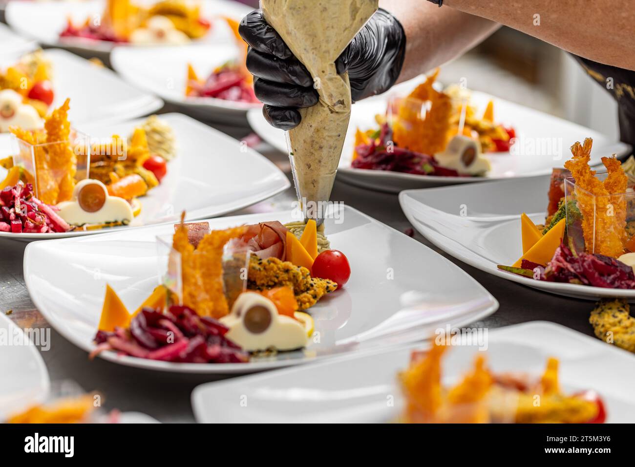 Chef is garnishing delicious appetizer dishes in restaurant kitchen ...