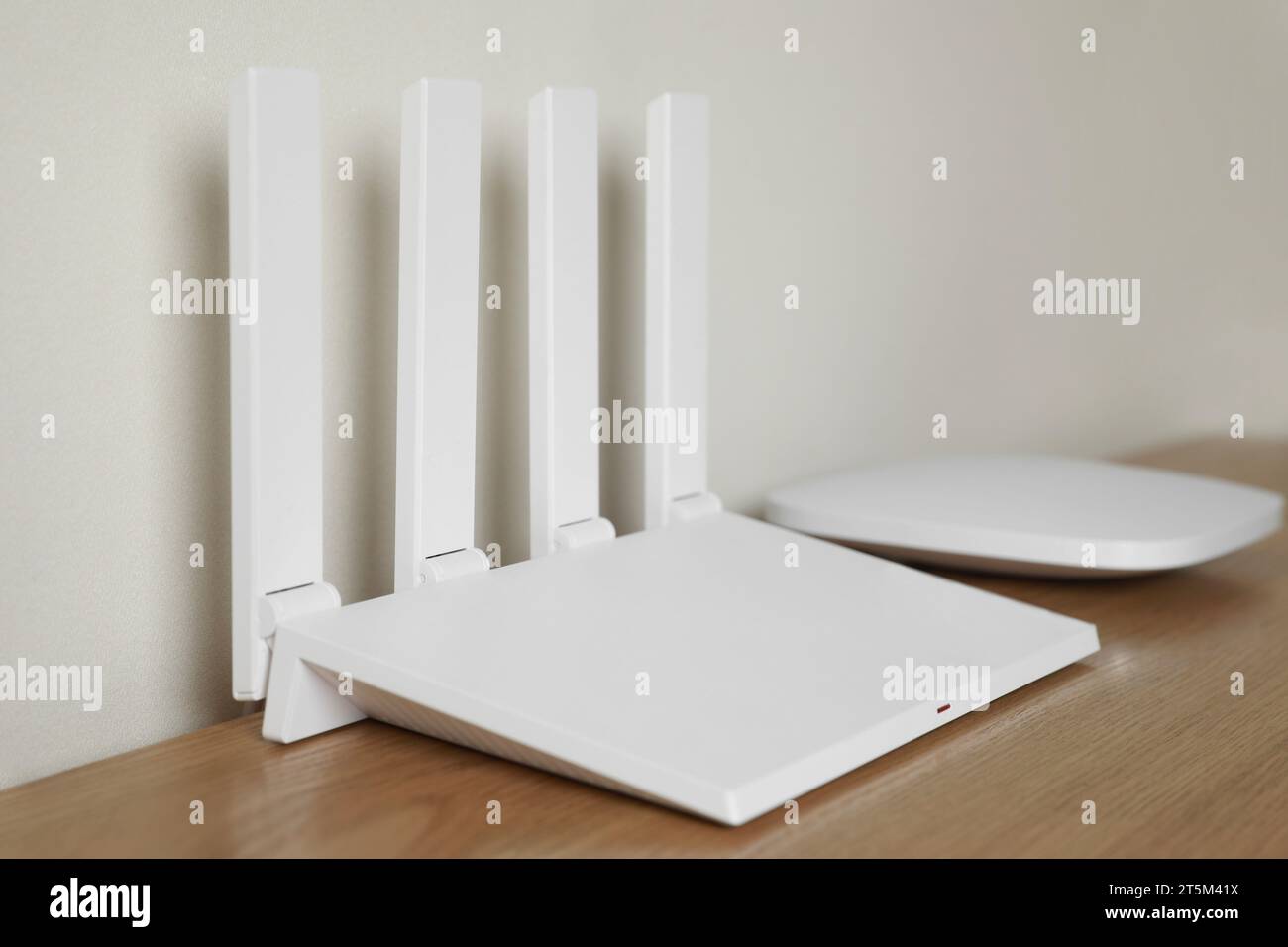 New modern Wi-Fi router on wooden table near white wall Stock Photo - Alamy