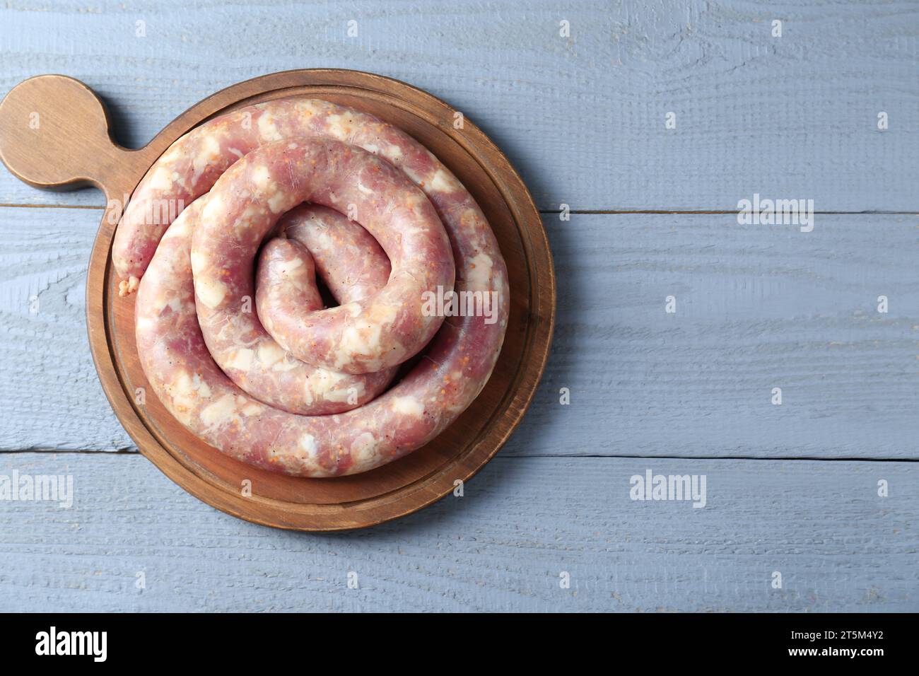 Homemade sausages on light grey wooden table, top view. Space for text ...