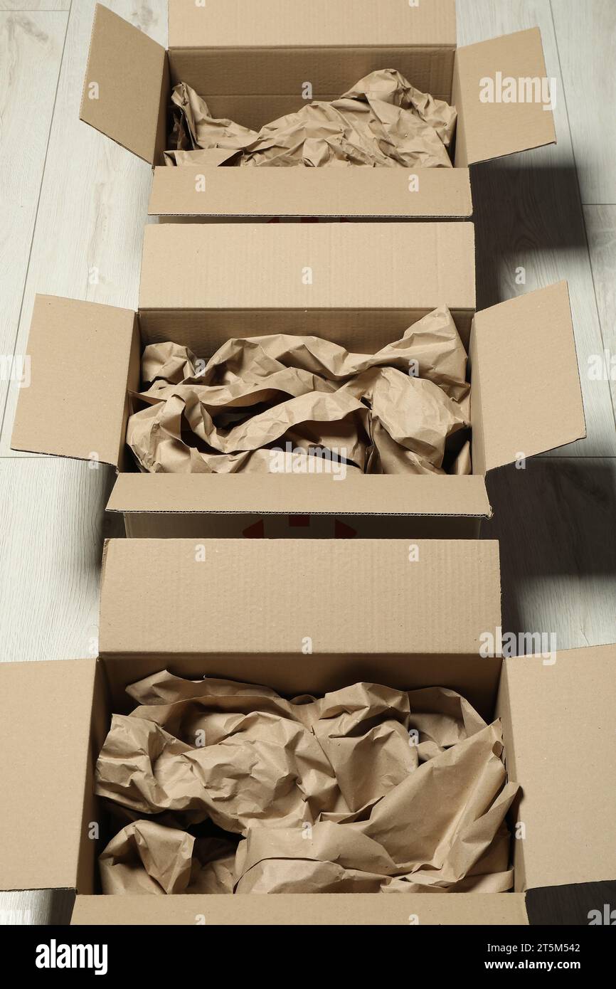 Open cardboard boxes with crumpled paper on white wooden floor Stock ...