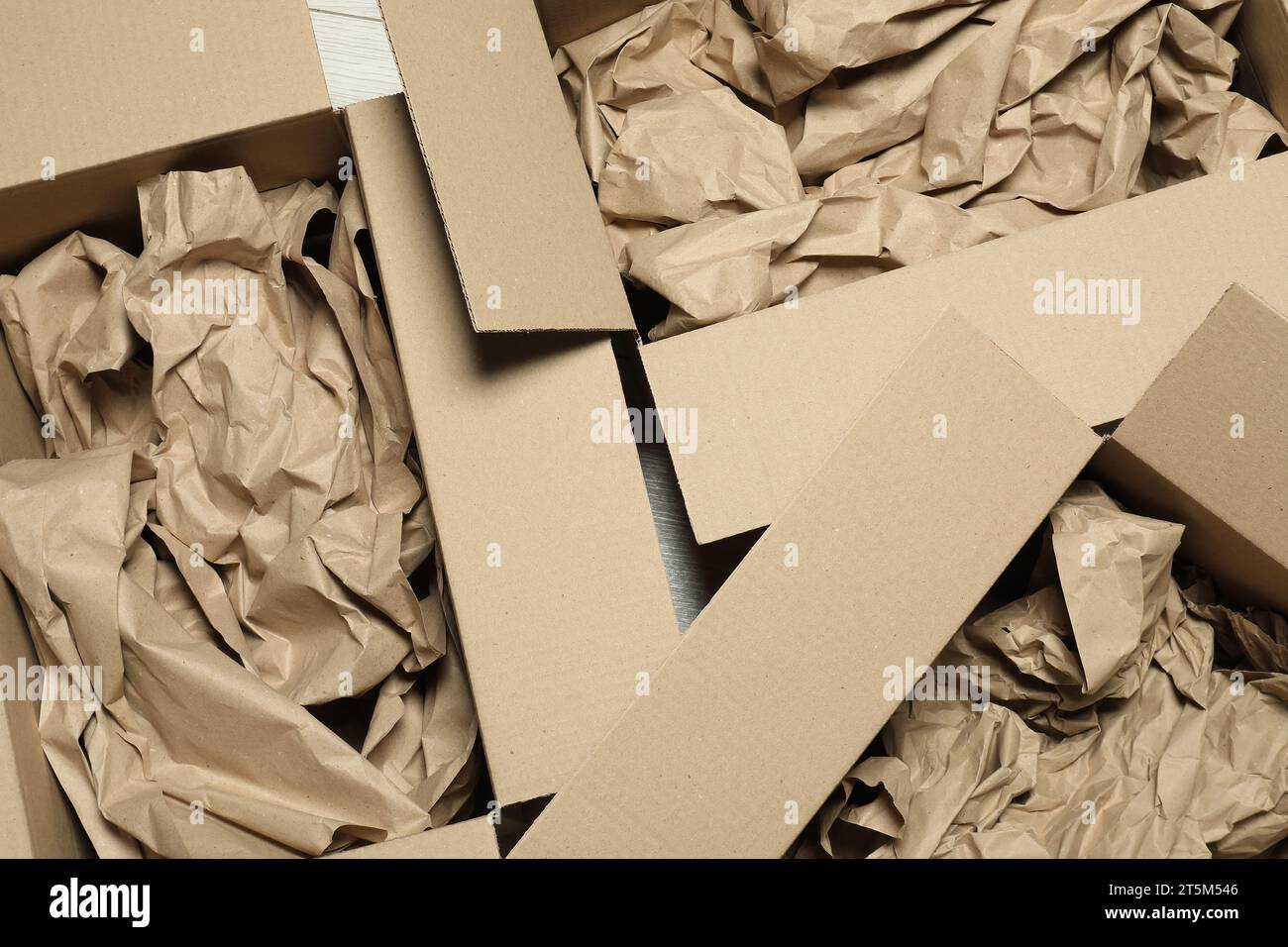 Open cardboard boxes with crumpled paper on white wooden floor, flat ...