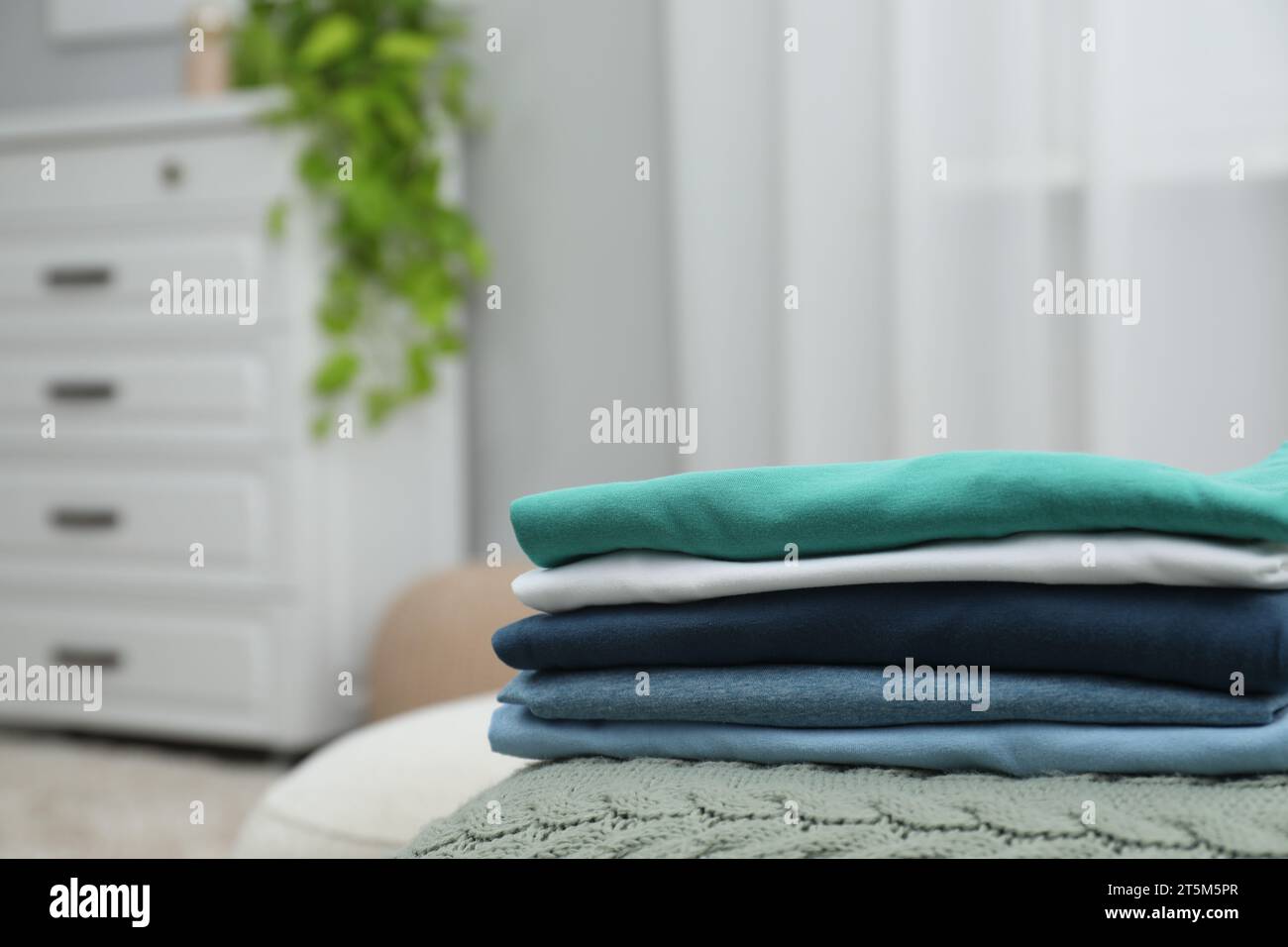 Sorting and organizing. Stack of different folded clothes on bed ...