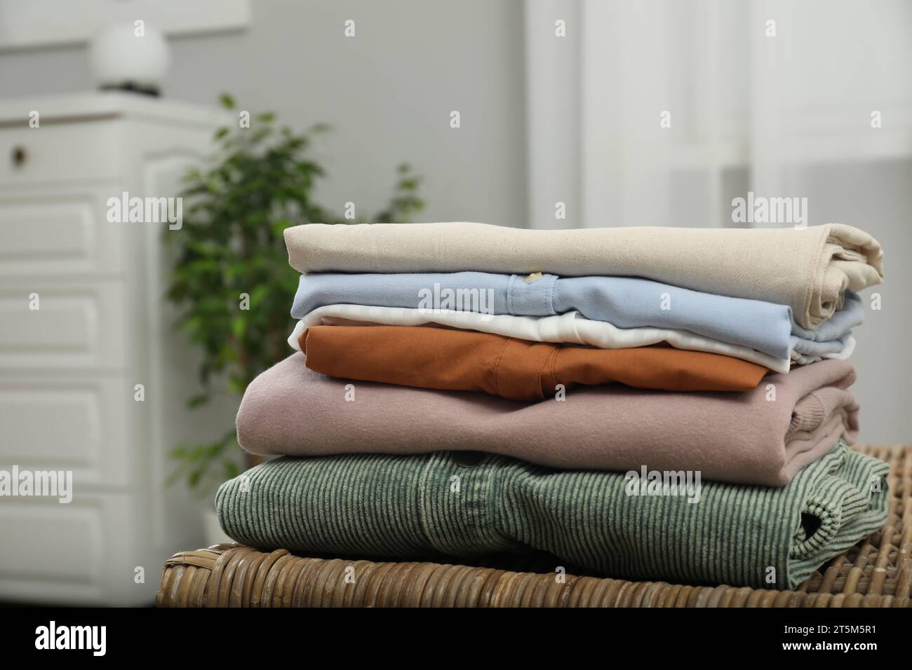 Sorting and organizing. Stack of different folded clothes on wicker ...