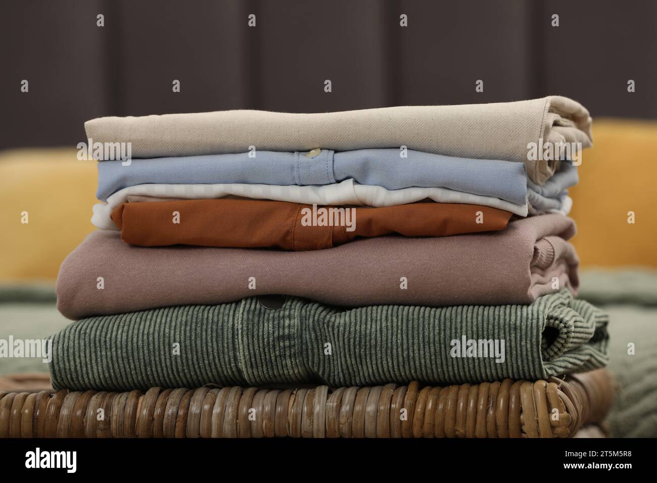 Sorting and organizing. Stack of different folded clothes on wicker ...