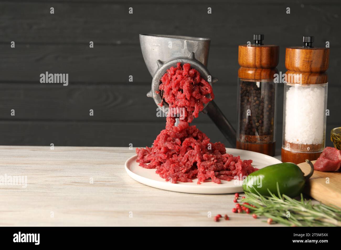 Metal meat grinder with minced beef, products and spices on light ...