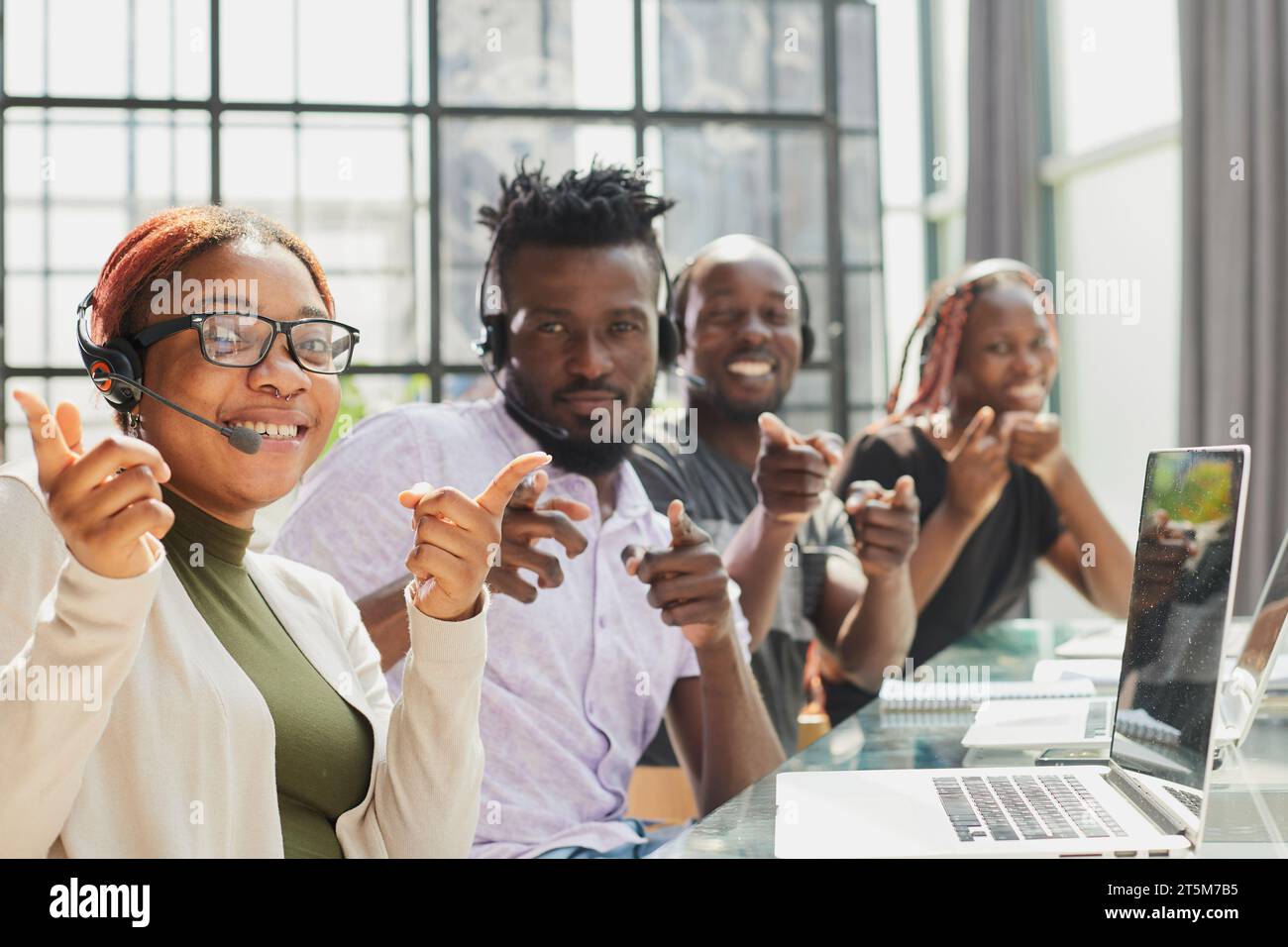 Young people in call center agent headphones pointing with finger at ...