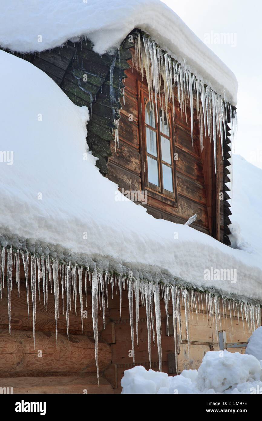 Old wooden house in a beautiful winter scenery. Huge icicles hang from ...