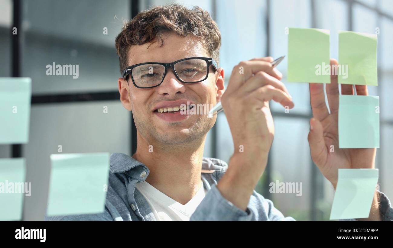 business man standing in front of stickers glass wall and write task on ...