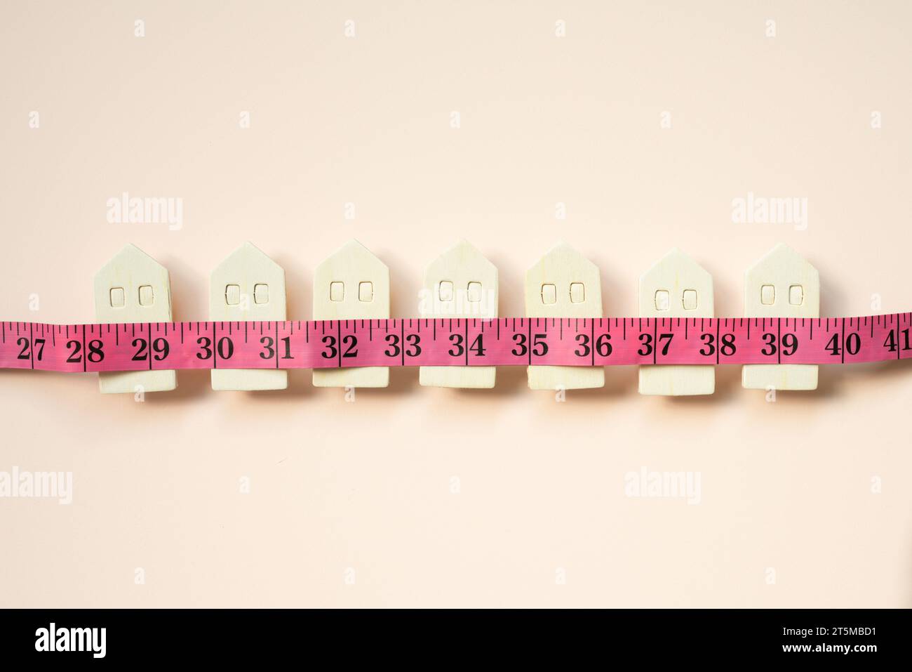 Miniature wood model house and tape measure on pink background. rental ...