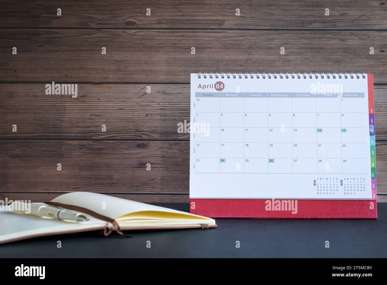 Desk standing calendar with notepad against wooden wall. Copy space ...