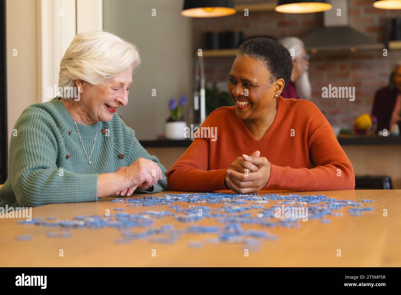 Happy diverse senior female friends playing with jigsaw puzzles in ...