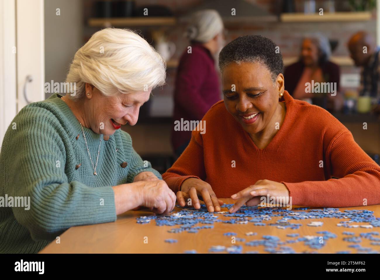 Happy diverse senior female friends playing with jigsaw puzzles in ...