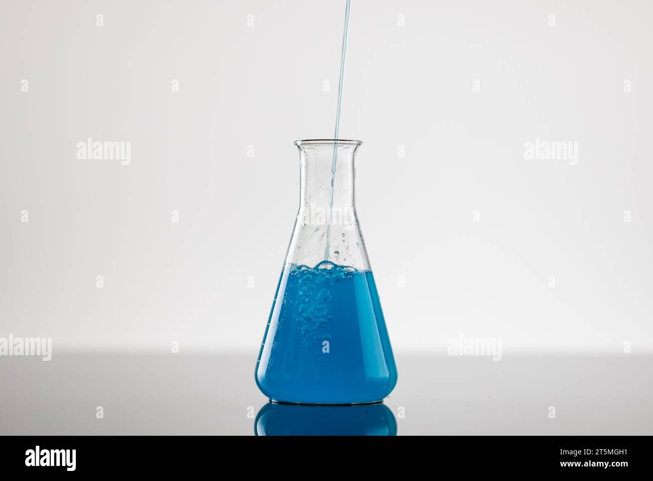 Close up of laboratory beaker with blue liquid and copy space on white ...