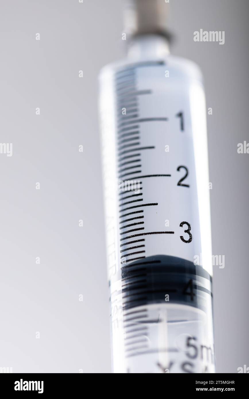 Vertical image of close up of laboratory syringe and copy space on grey ...