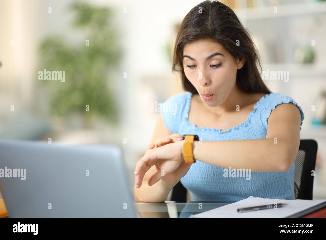 Surprised student checking smartwatch at home Stock Photo - Alamy