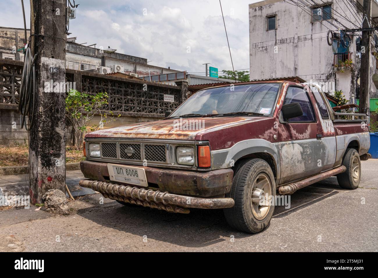 An old Nissan pickup truck is rusty and ancient on the street in ...