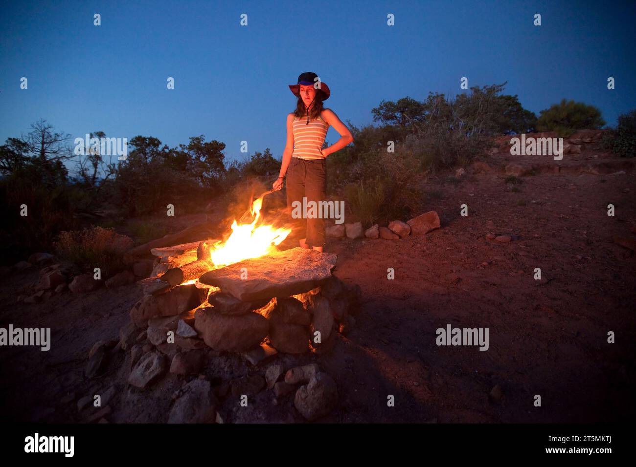 A woman standing next to a camp fire Stock Photo - Alamy