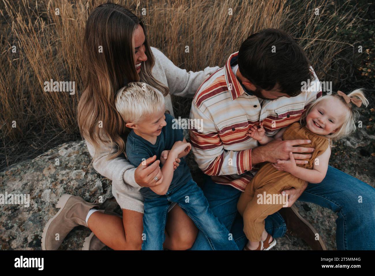 Family of four hugs and laughs on a rock Stock Photo - Alamy