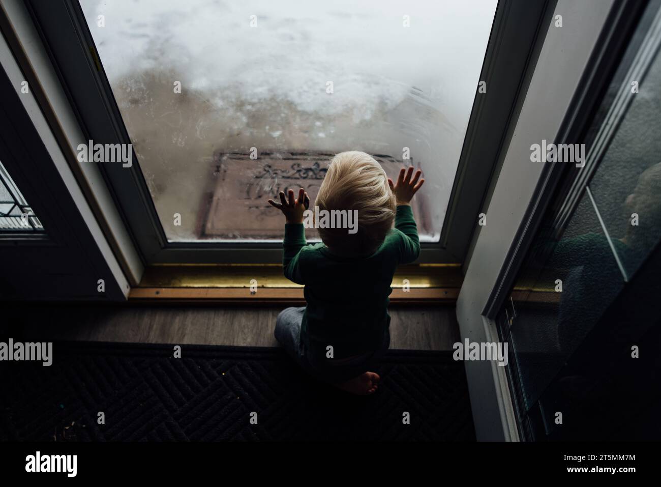 Overhead view of little boy pressing hands against window and lo Stock ...