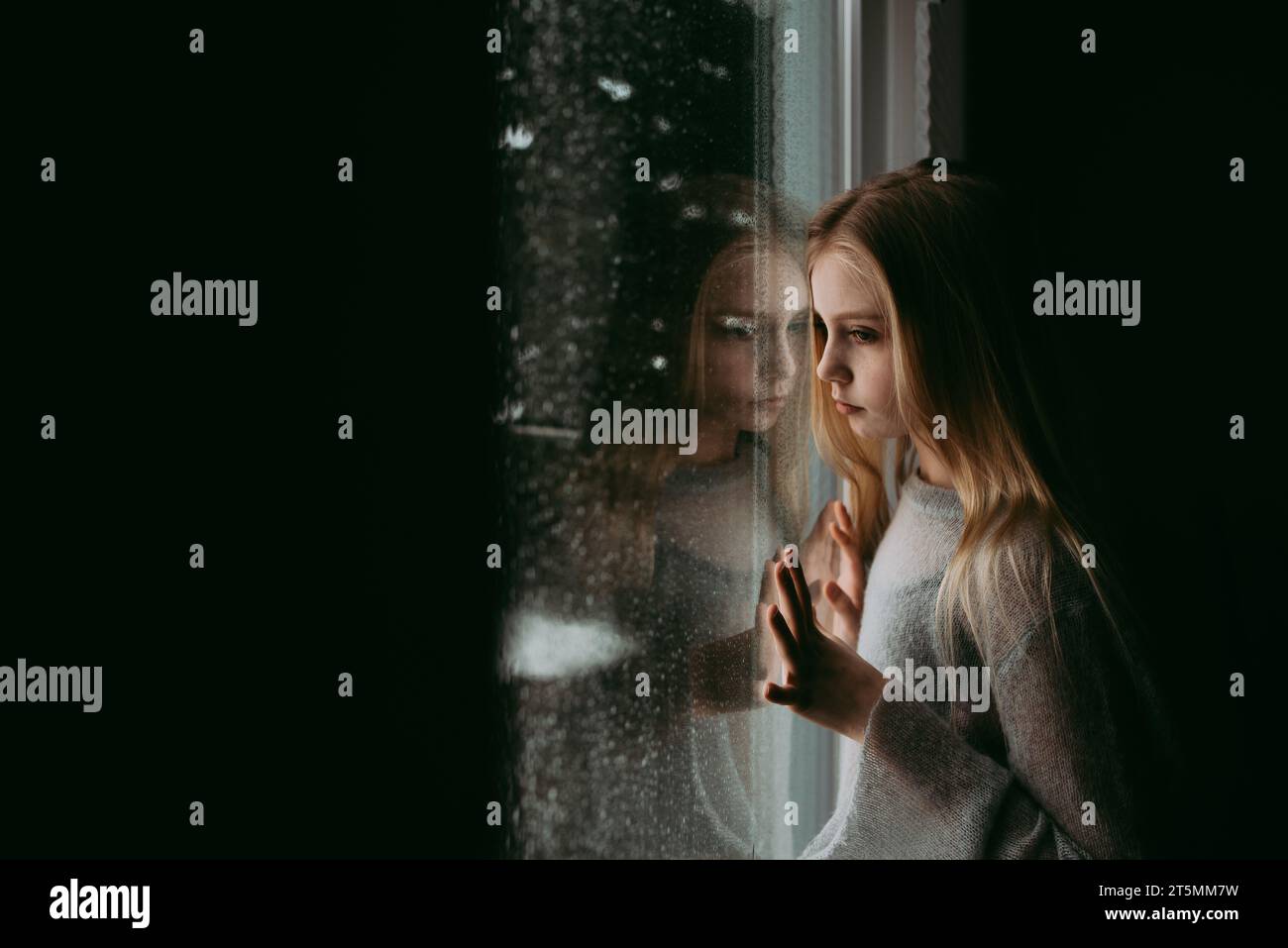 Dramatic side view of teen girl leaning against window with refl Stock ...