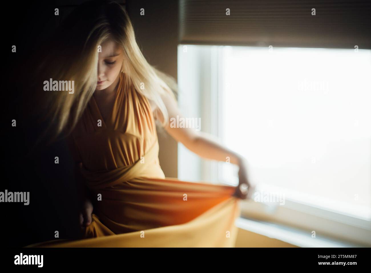 Preteen girl standing in front of bright window while spinning i Stock ...