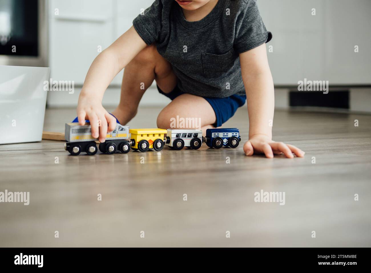 Low side view of small child playing with lined up wooden trains Stock ...